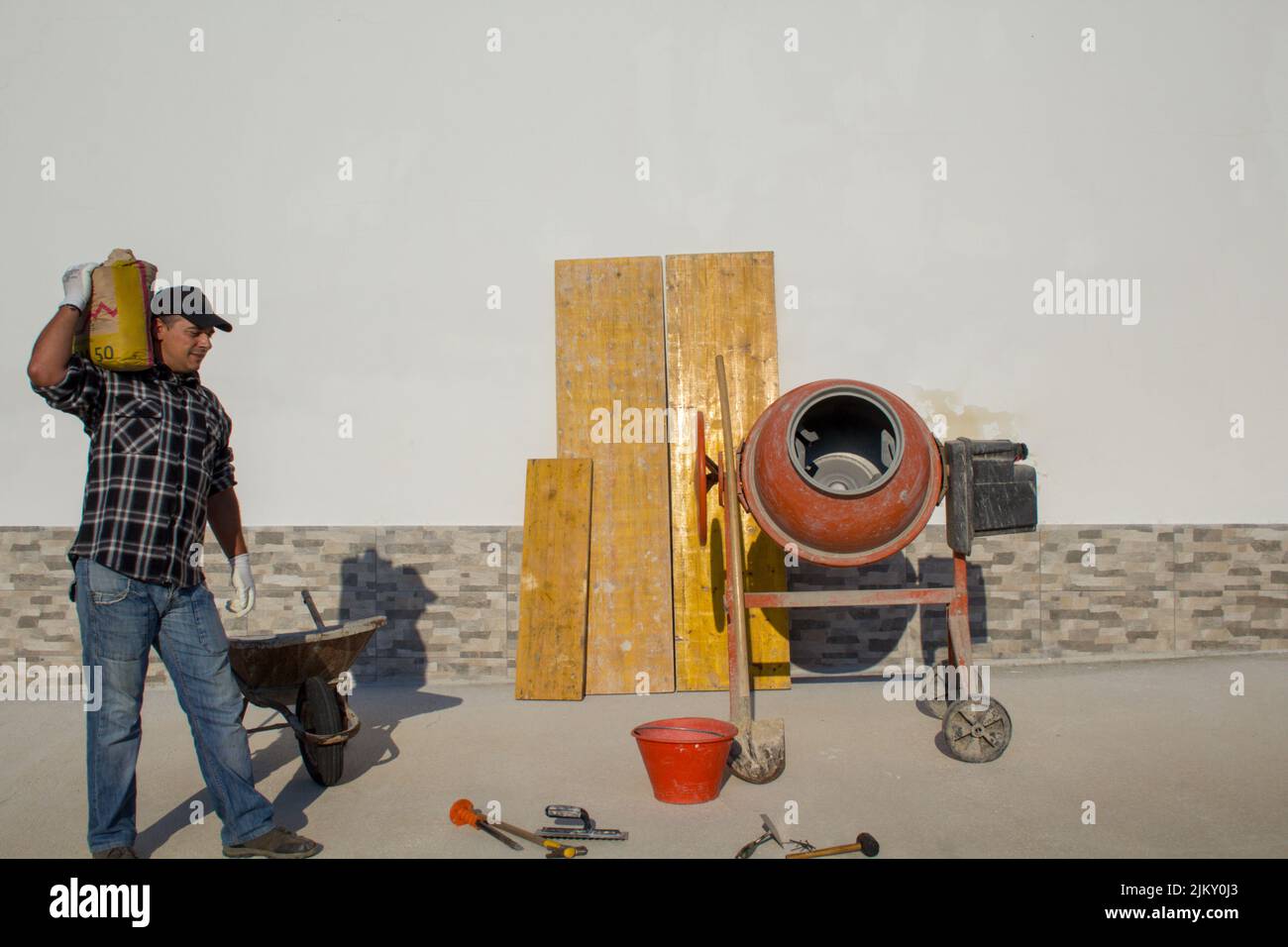 Image of a construction worker carrying a sack of cement on his ...