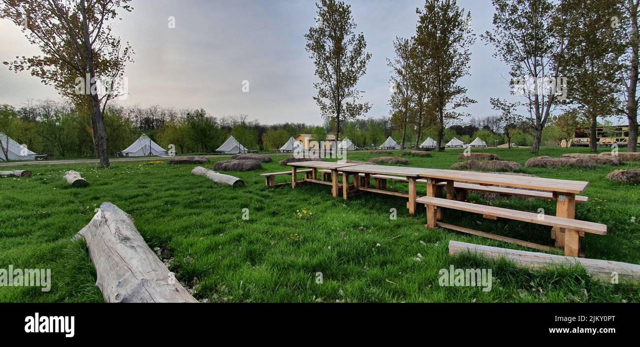 The wide angle shot of a camping resort with wooden benches and tables ...