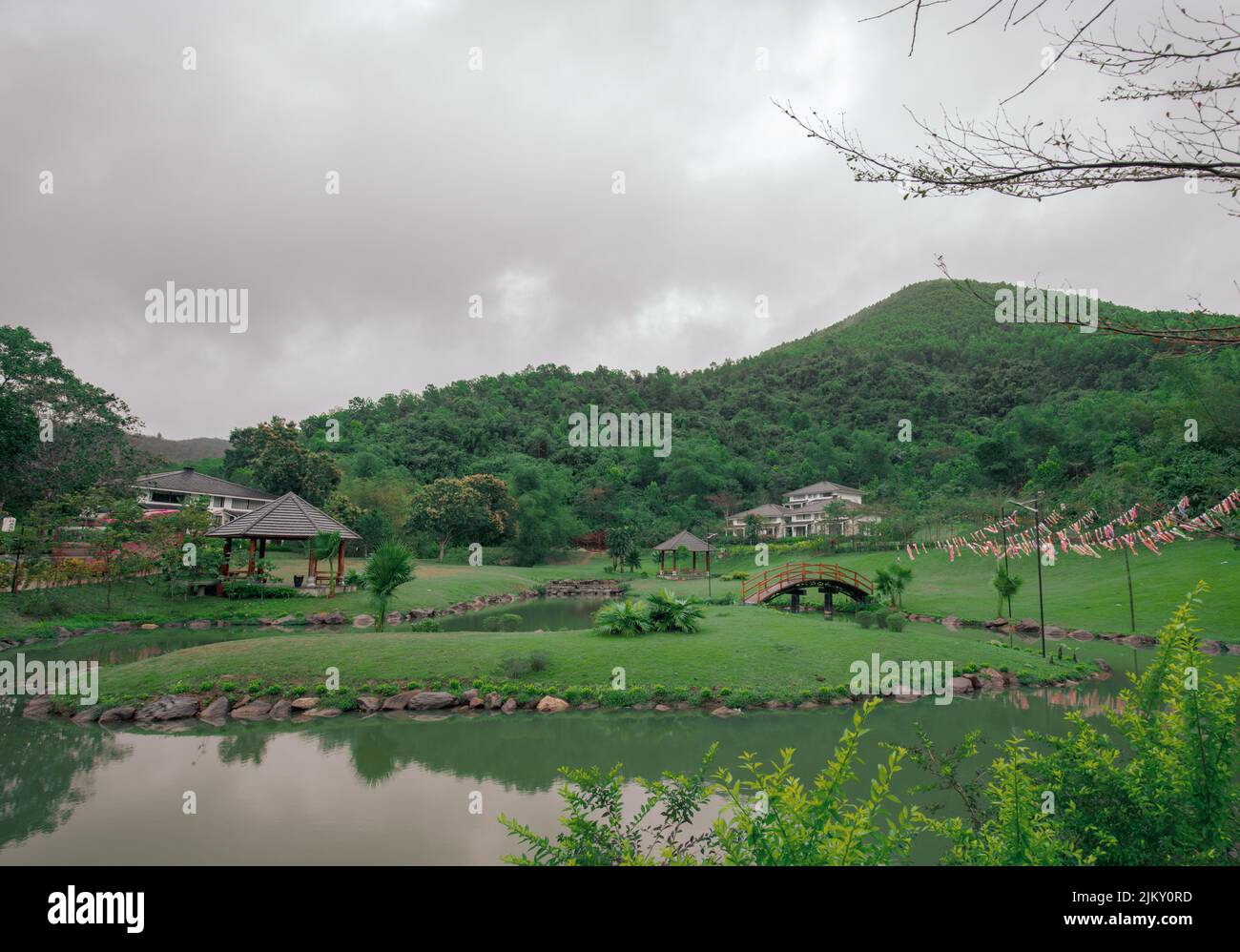 A view of a beautiful green area with pavillions and hills and a pond ...