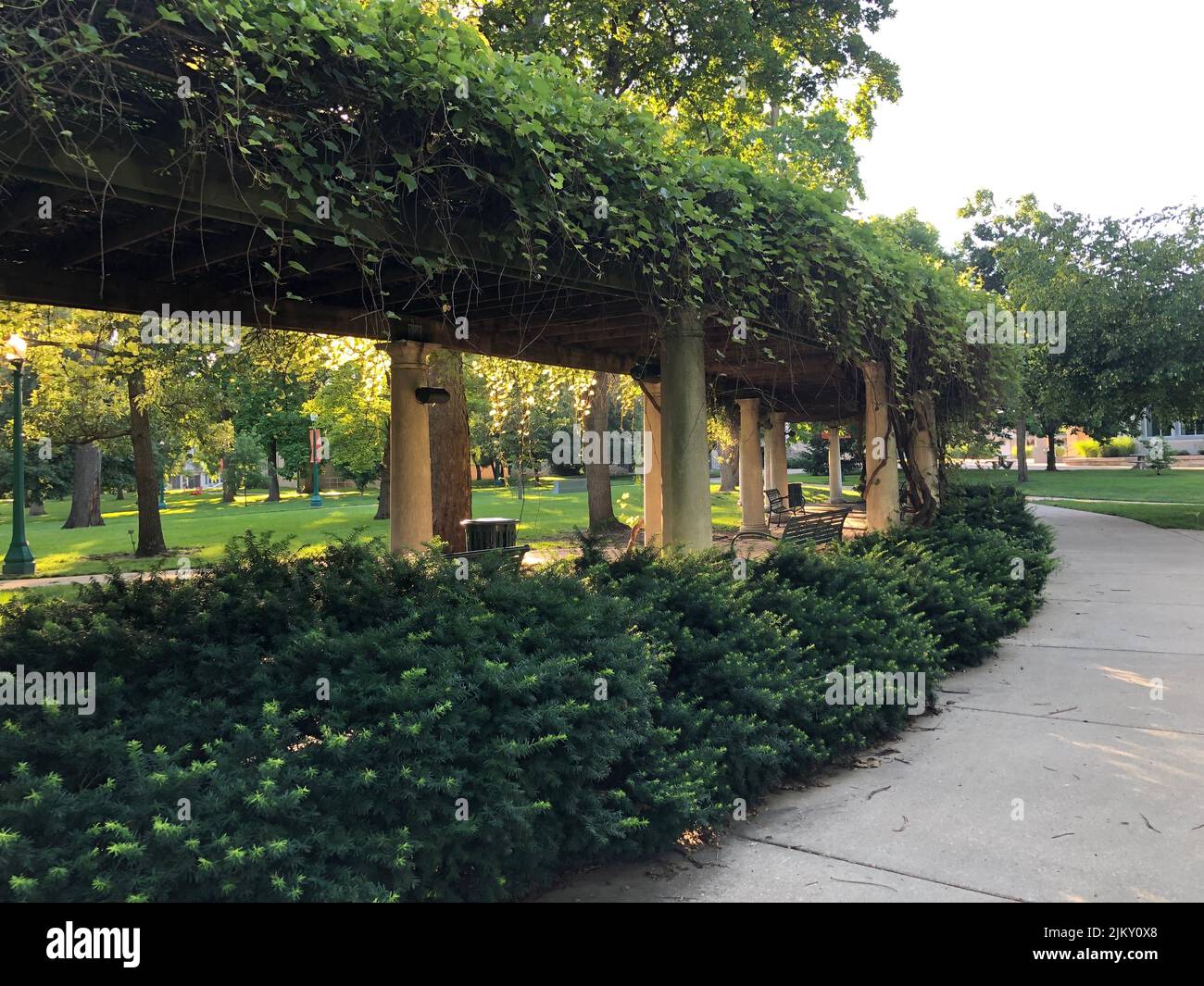 A park with covered trail with columns and benches surrounded by ...