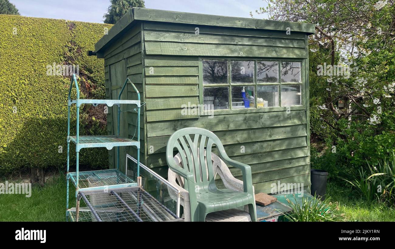 An old green colored wooden shed with a little window in the garden ...
