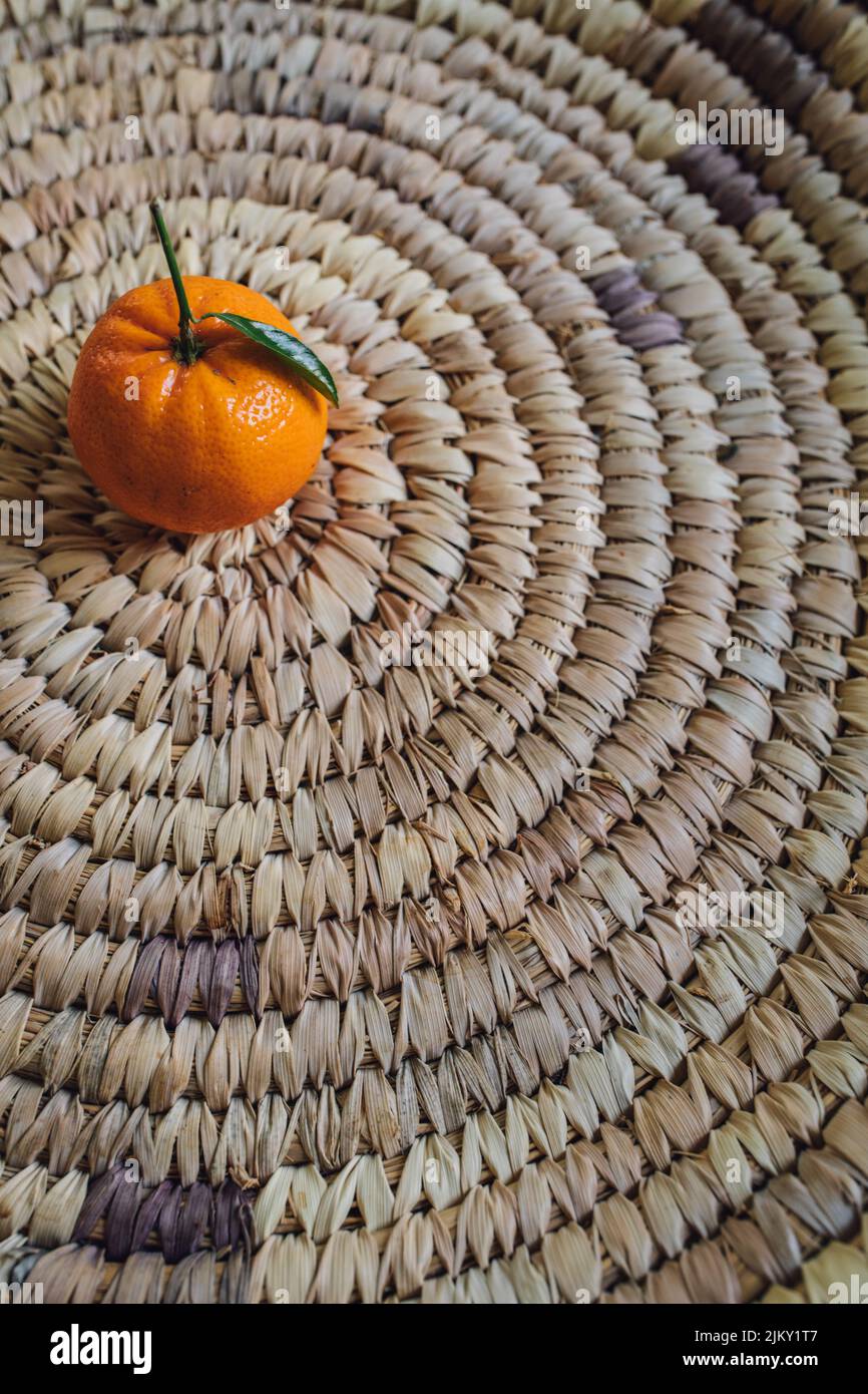 single orange in the middle of Iraqi craft woven basket with purple ...