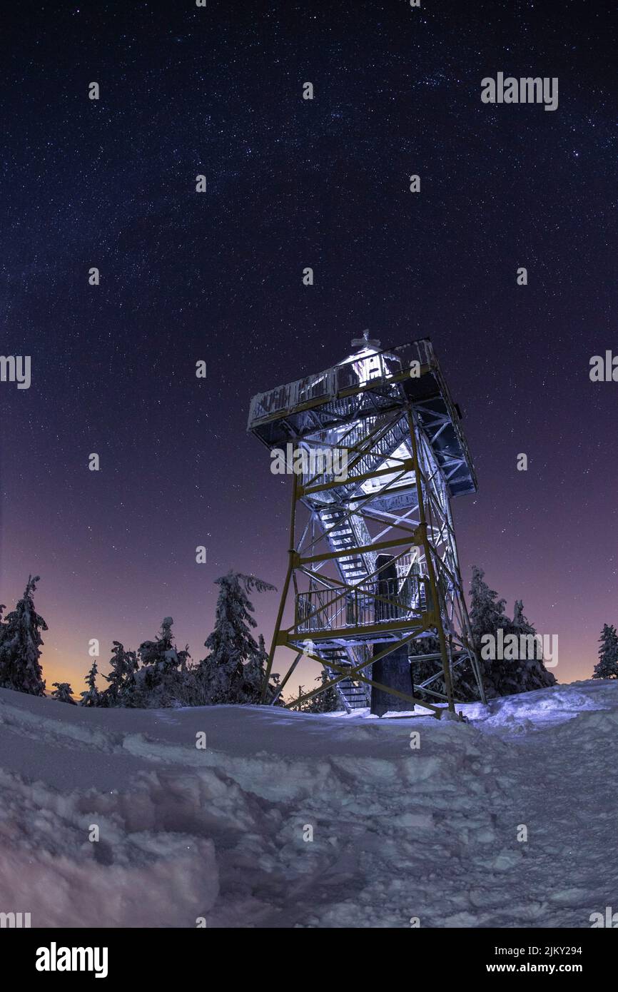 A vertical shot of a viewing tower at night with a starry sky ...