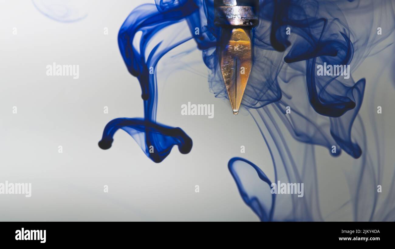 A fountain pen and blue ink liquid in water make an abstract forms ...