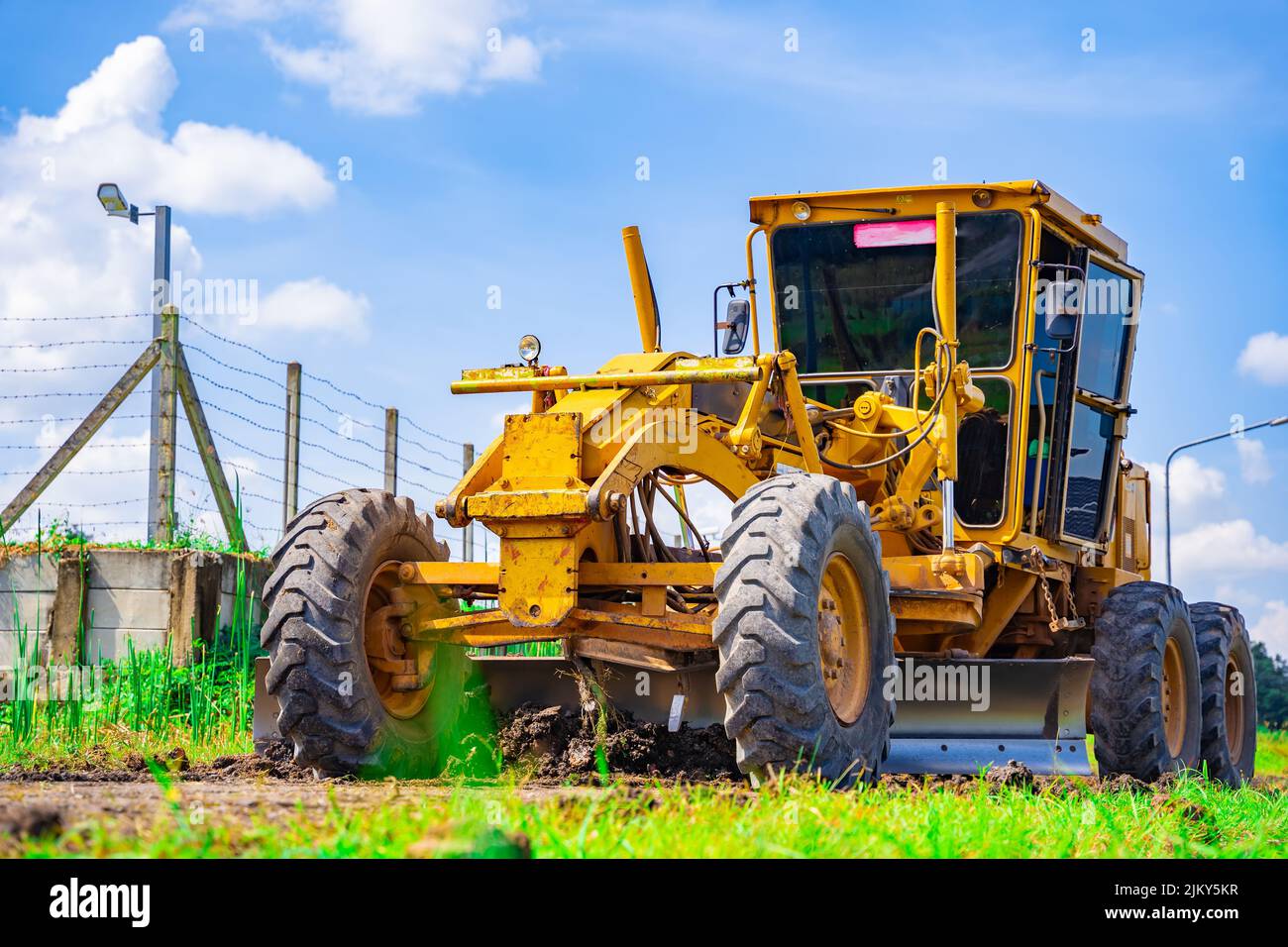 The ground grader is adjusting the road surface evenly to the level ...