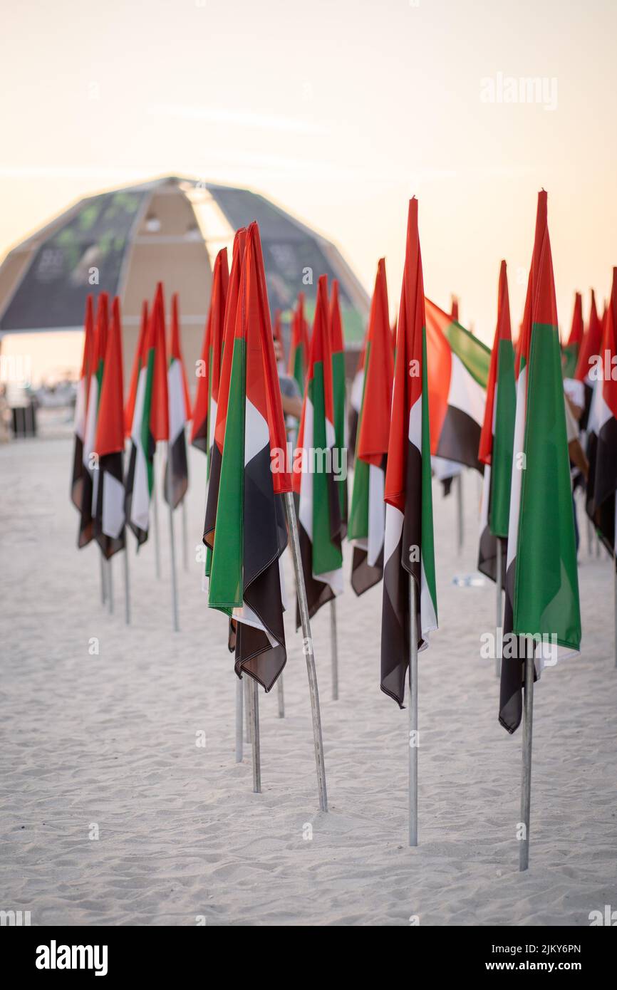 A vertical shot of a bunch of UAE flags on poles on Kite Beach in Dubai ...