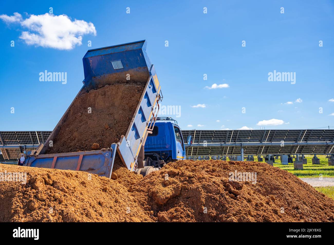 A blue six-wheeled vehicle is pouring orange soil onto the floor of an ...