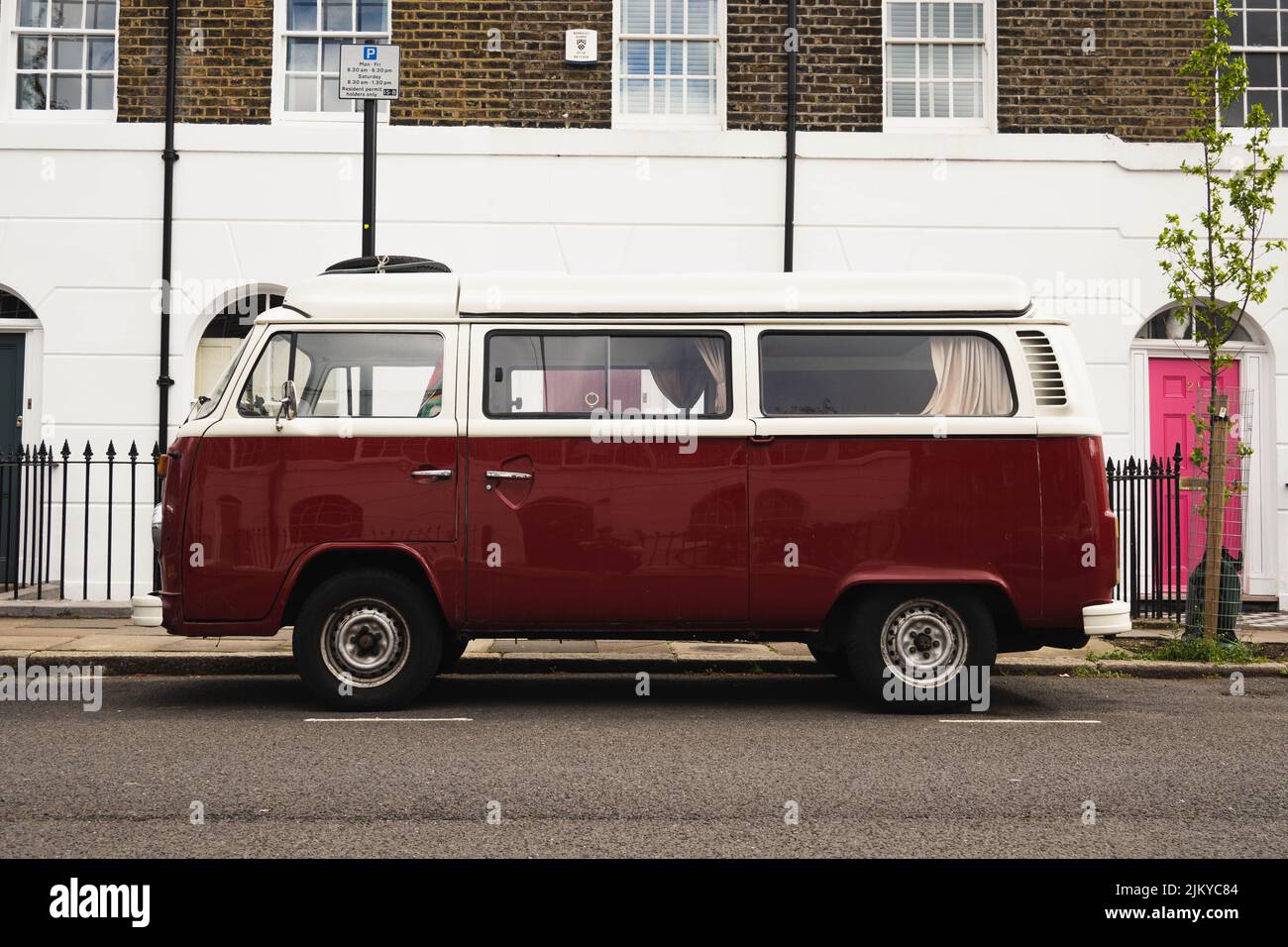 A beautiful white and brown van parked in front of residential building ...