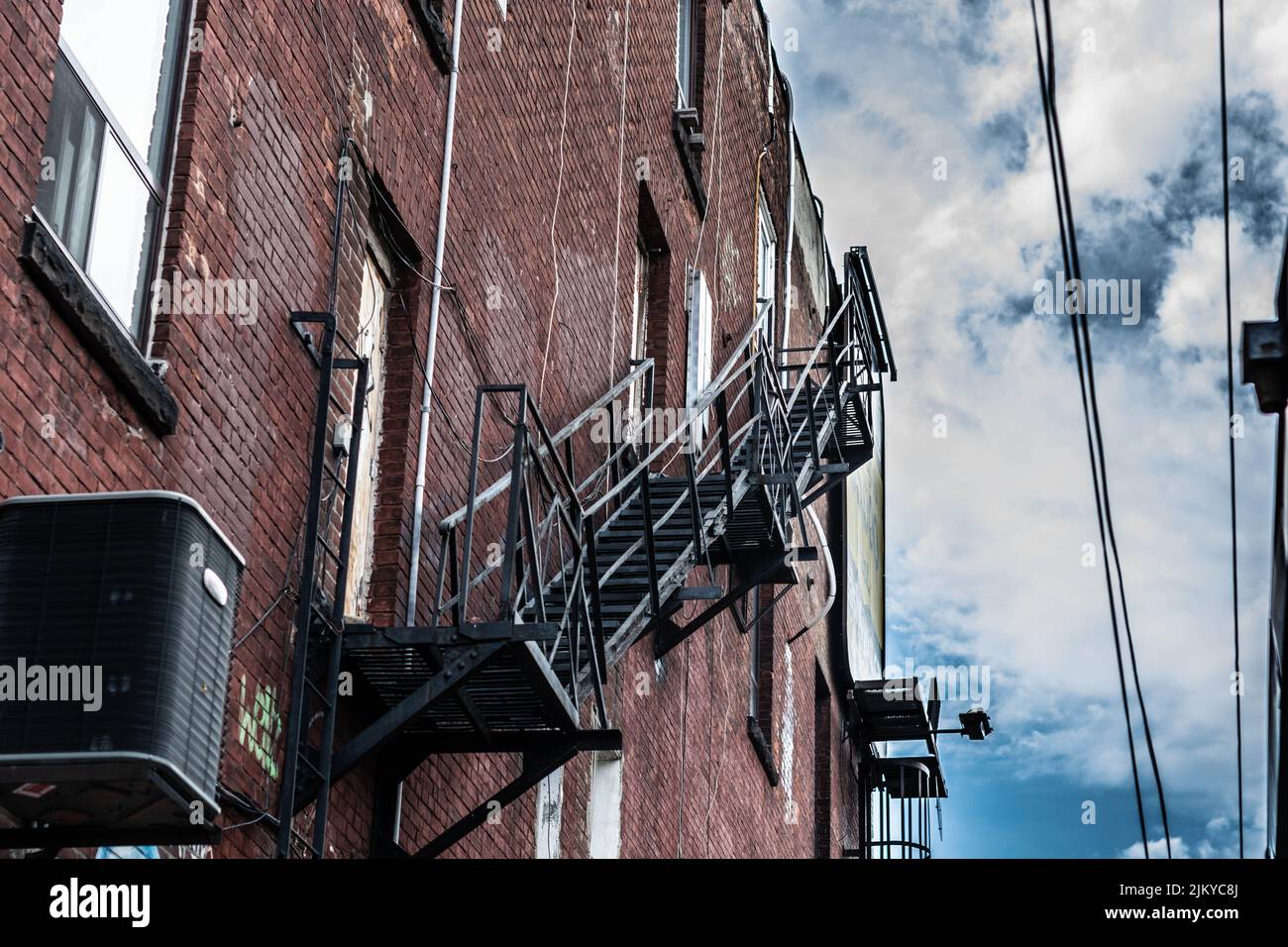 A low angle shot of a red brick building with metal fire escape stairs ...