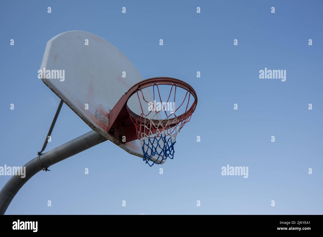 A low-angle shot of a basketball hoop against the blue sky in the ...