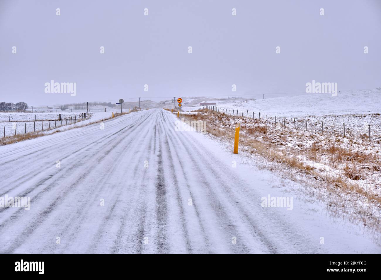 Long straight road covered in snow leading into snowy white distant ...