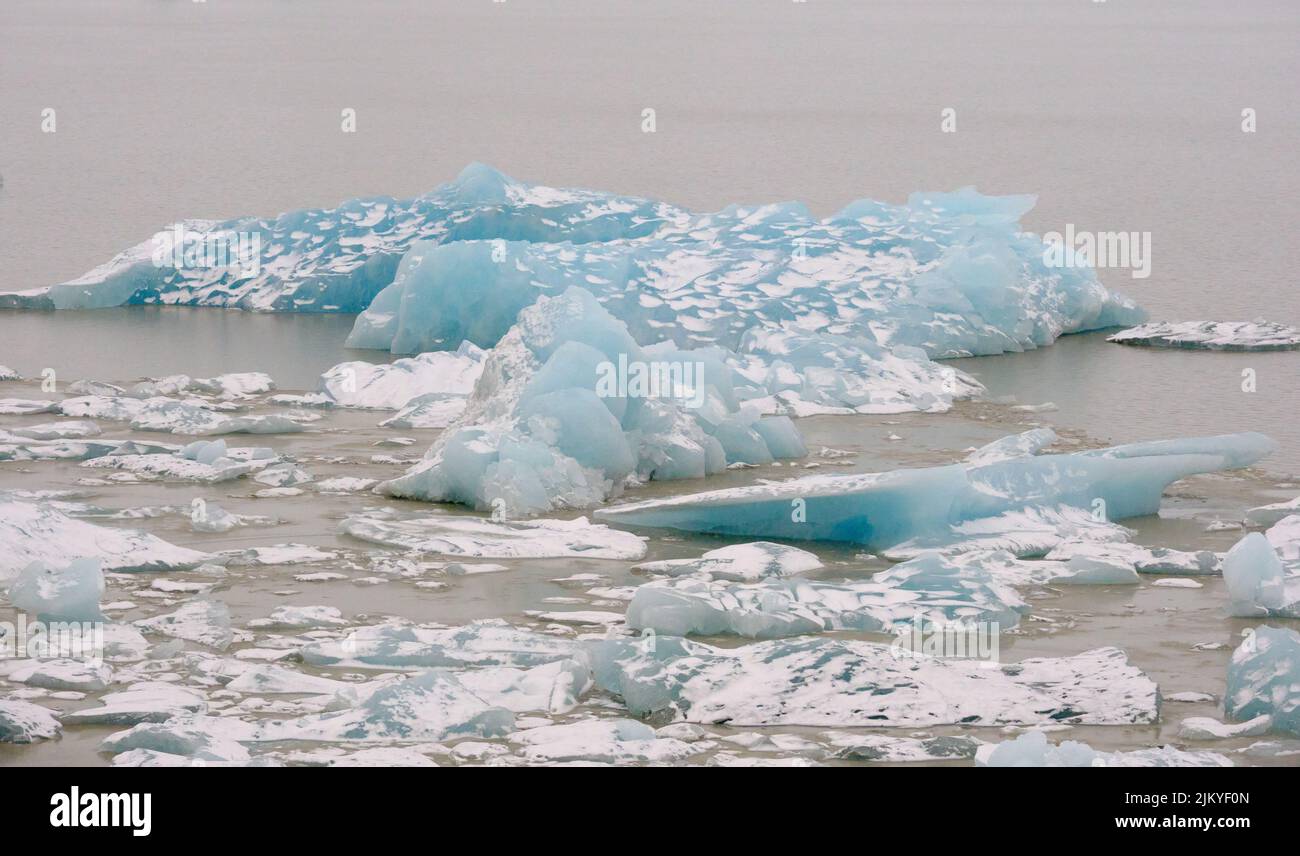 Large blue iceberg floating on brown water of Fjallsarlon Glacier Lake ...