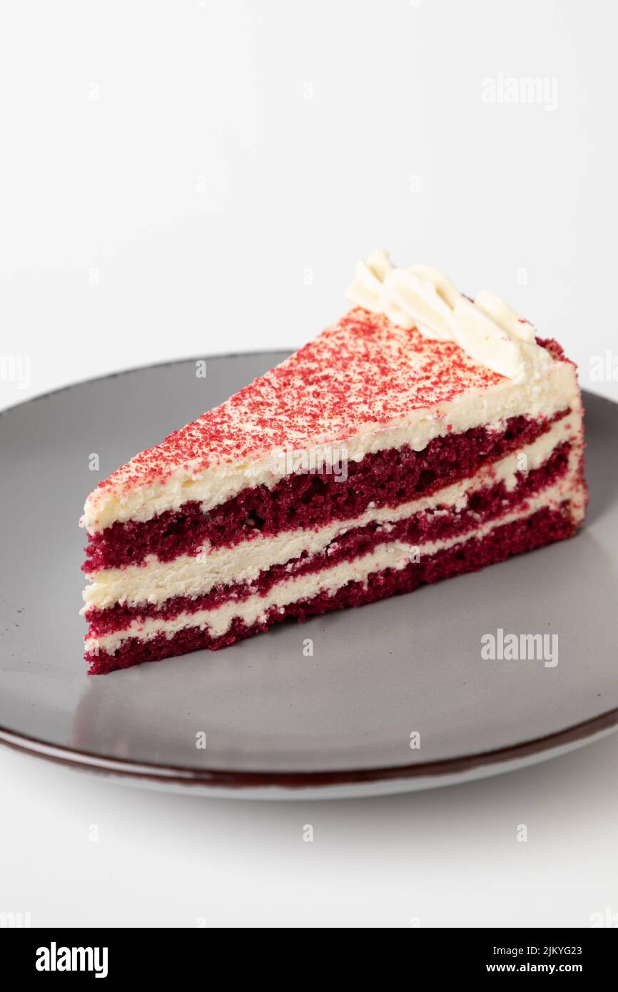 A vertical shot of a slice of red velvet cake on a gray plate isolated ...