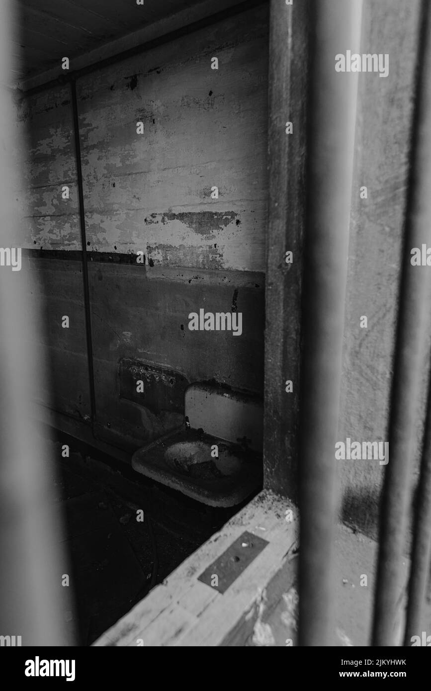 A grayscale depth focus shot through the metal bars of a room in an ...
