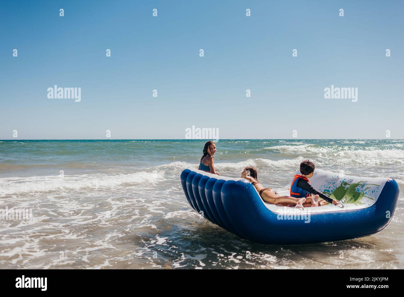 Kids playing and surfing in on the beach in small waves. Grandmothers ...