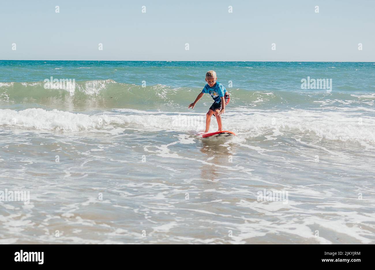 Kids playing and surfing in on the beach in small waves. Grandmothers ...