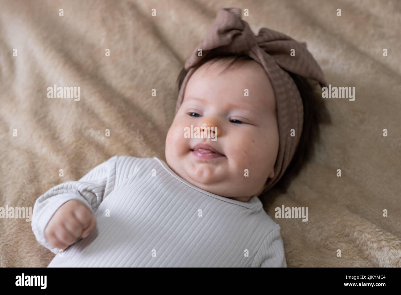 A closeup of a cute newborn baby girl lying on a beige blanket Stock ...