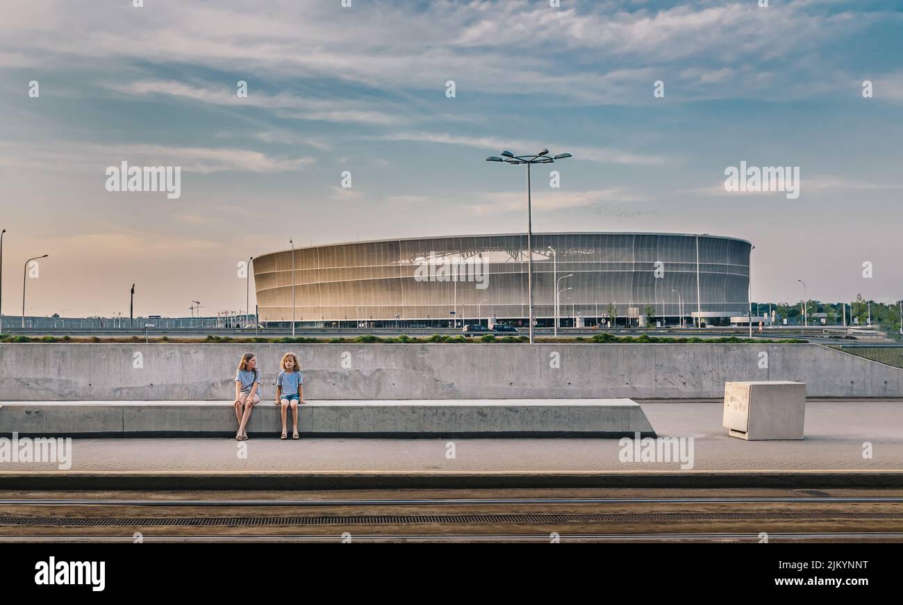 A beautiful two kids sitting with Tarczynski Arena Stadium in the ...