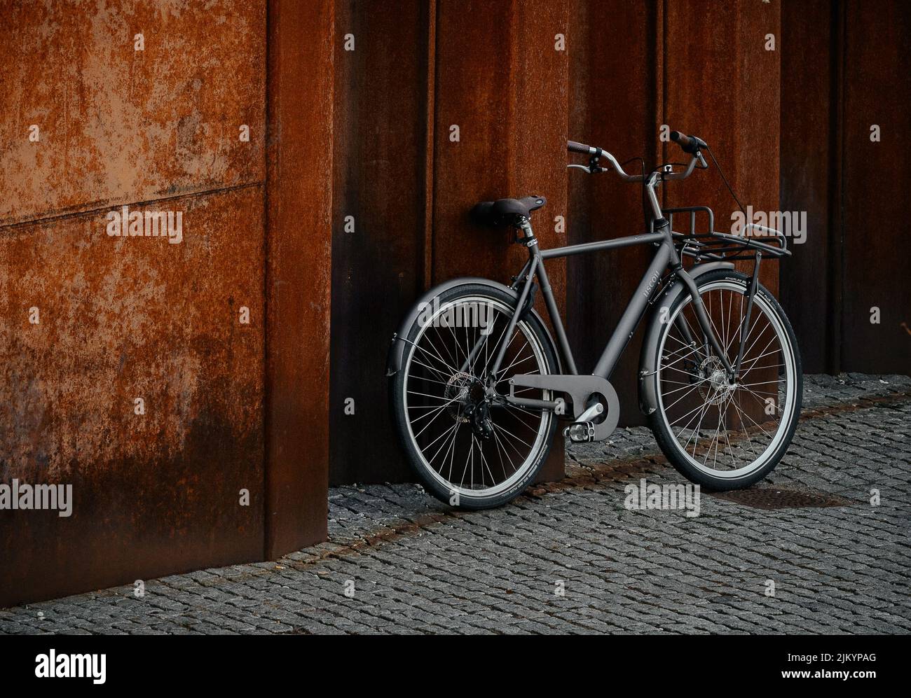 A modern parked bicycle near the wooden walls on the textured grey ...
