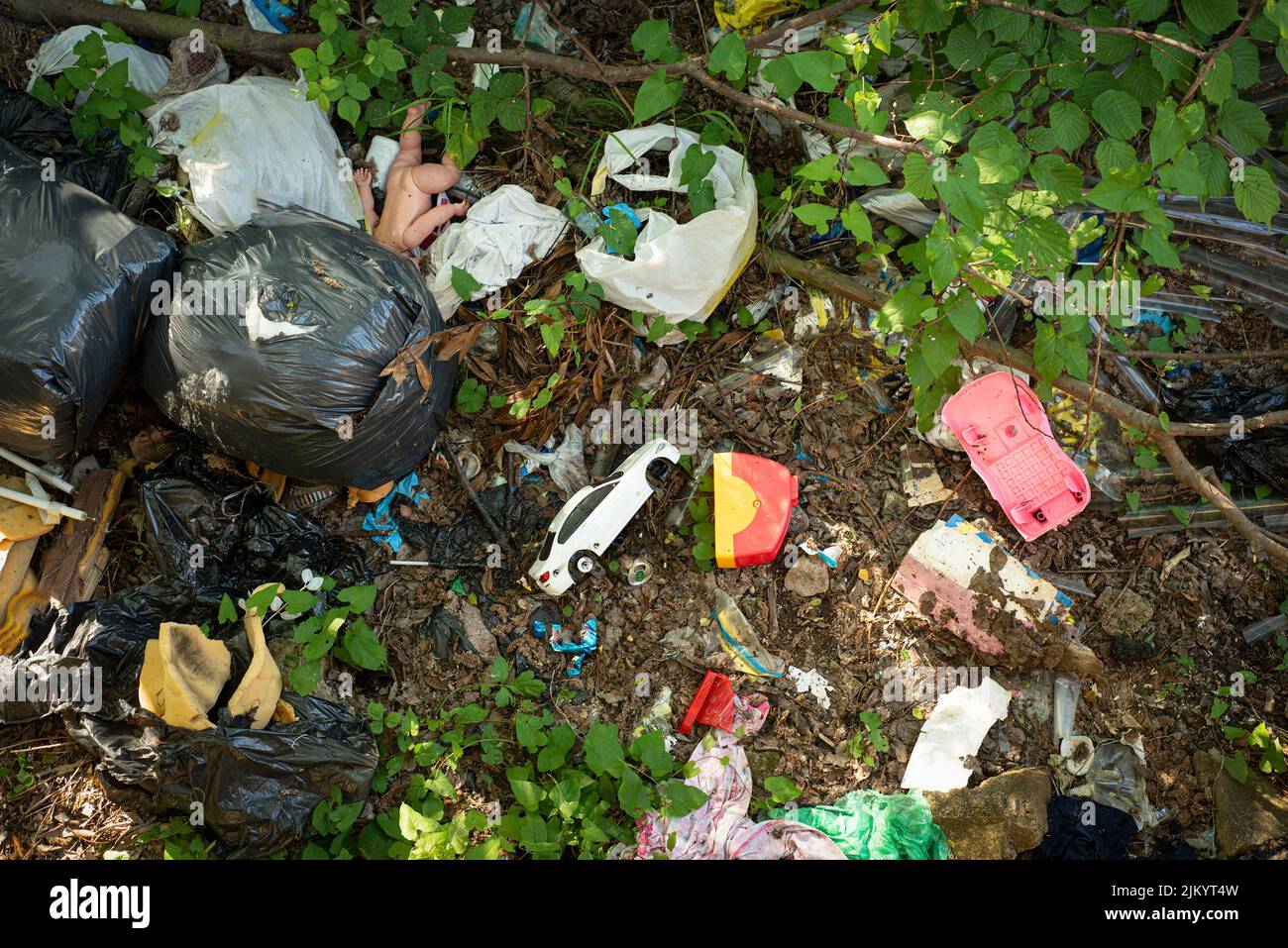 Fly tipping of garbage in urban woodland next to road Stock Photo - Alamy