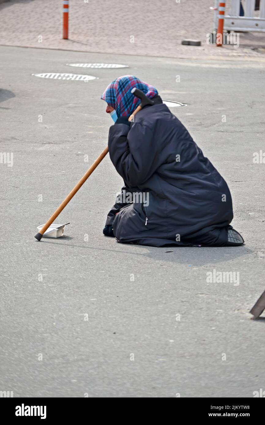 elderly grandmother with striped headscarf and stick in black suit ...