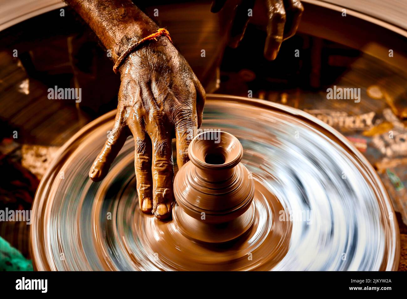 A slow shutter speed shot of a potter hand making a pot from a pottery ...
