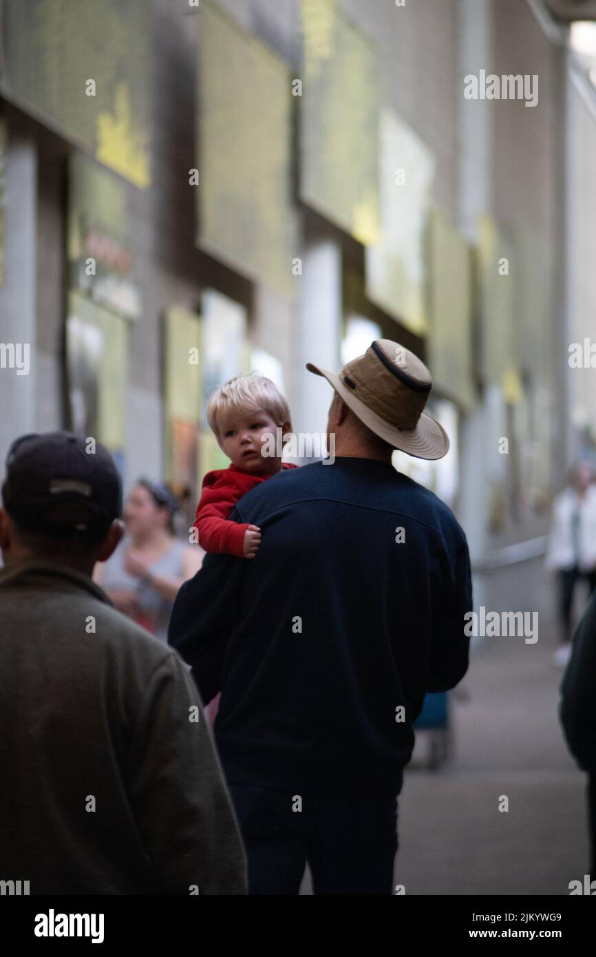 A Caucasian man with a cowboy hat carrying his son on the street Stock ...