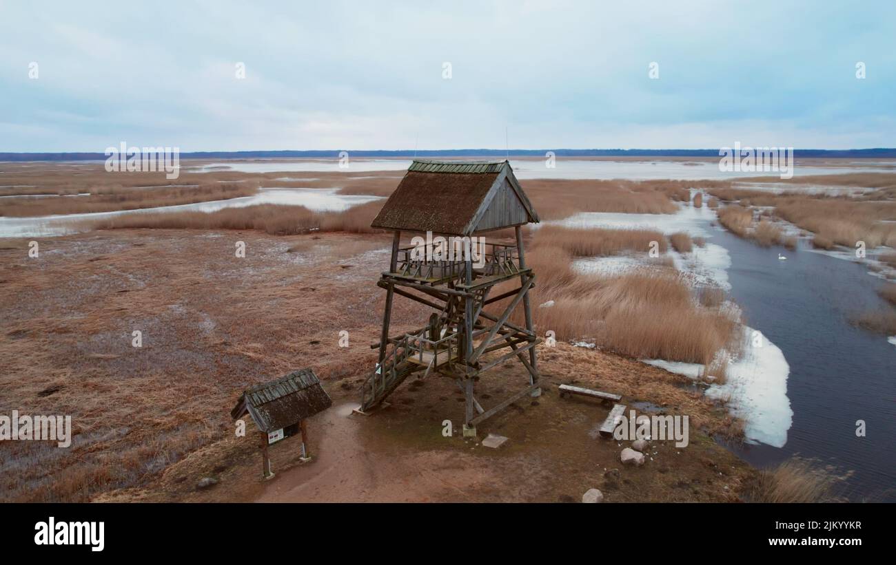 An aerial view of an old wooden watchtower by a swamp under a blue ...
