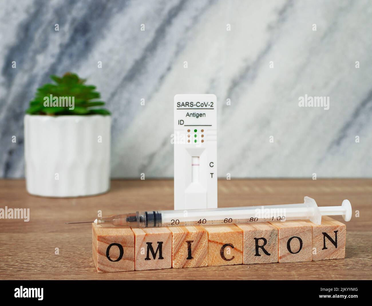 A closeup of a Covid-19 antigen test and a syringe on wooden blocks ...