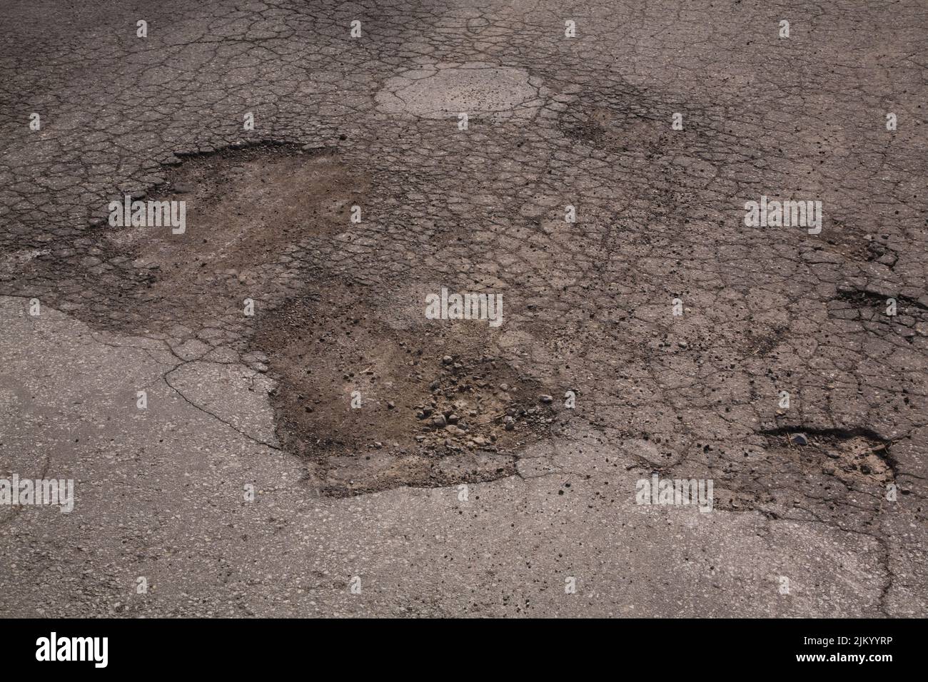 Close-up of cracked asphalt pavement with potholes Stock Photo - Alamy