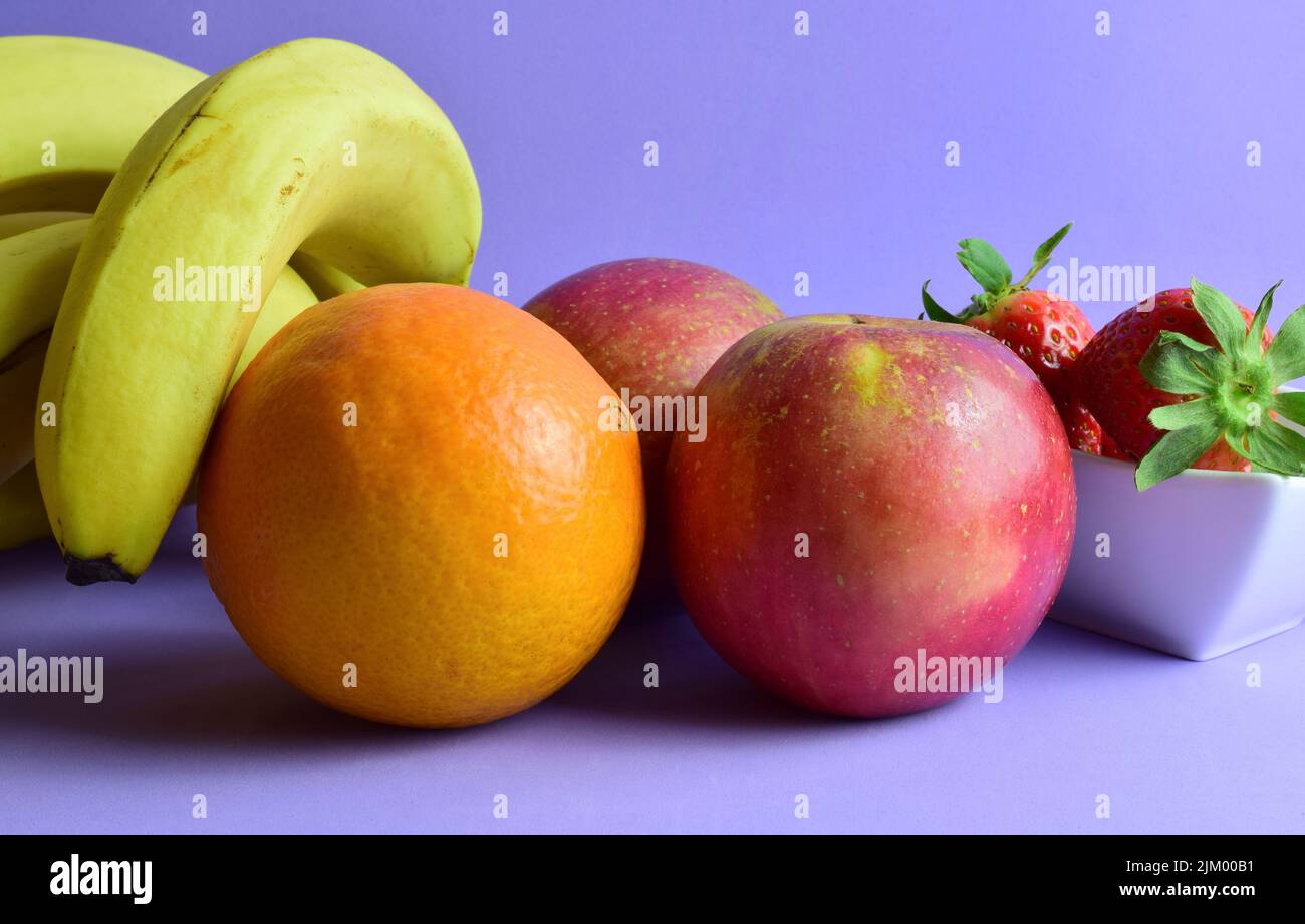 A closeup of various fruits full of vitamins on a purple background ...