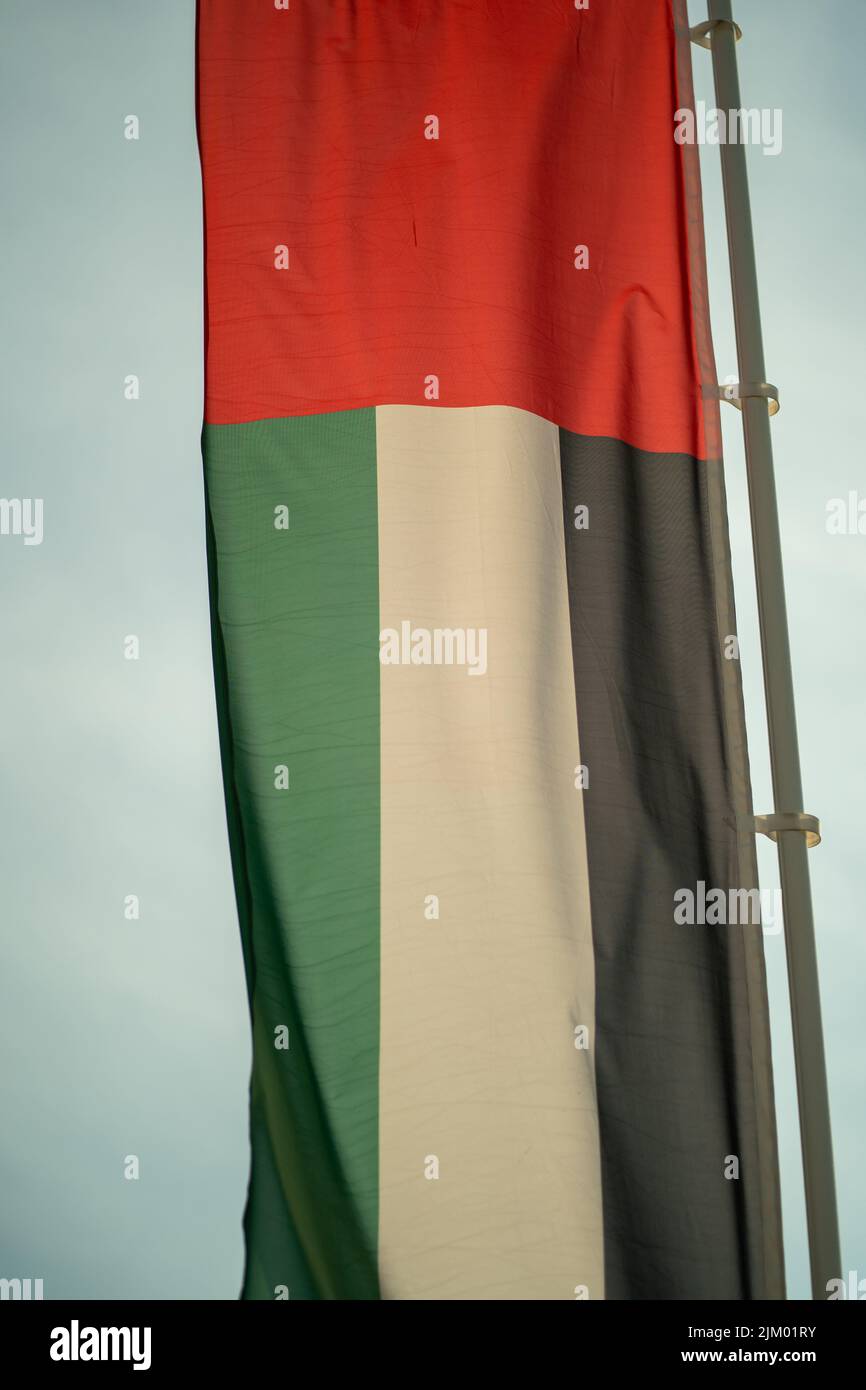 A beautiful shot of the UAE flag hanging vertically on a metal pole ...