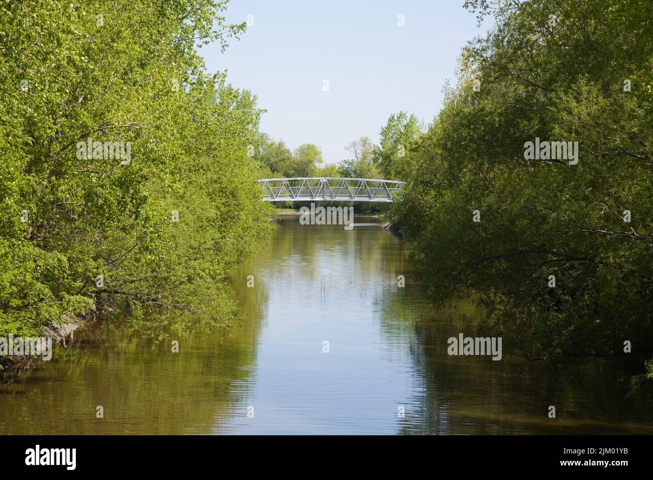 Footbridge over river bordered with deciduous trees in spring Stock ...
