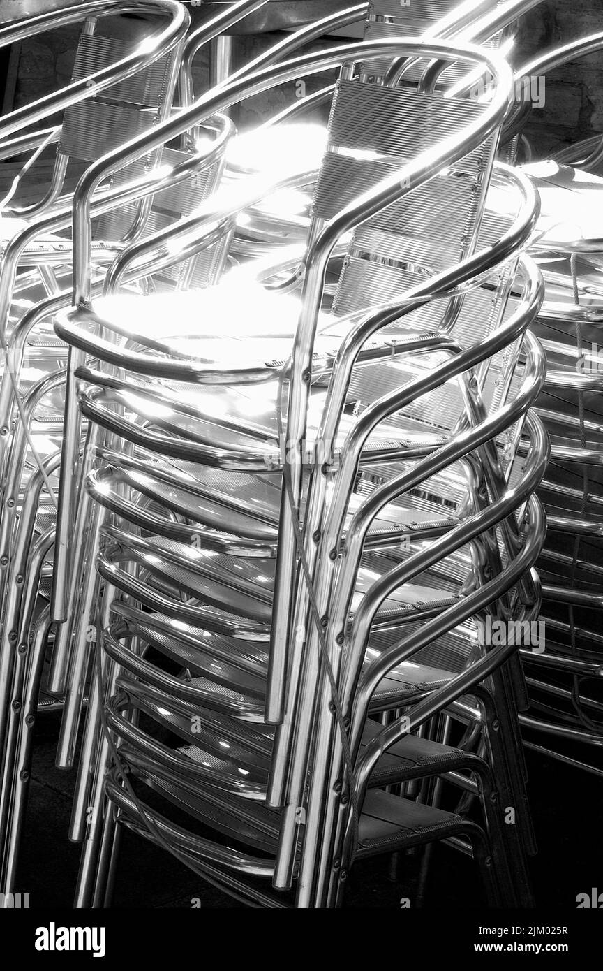 A vertical grayscale shot of a stack of chairs on top of each other ...