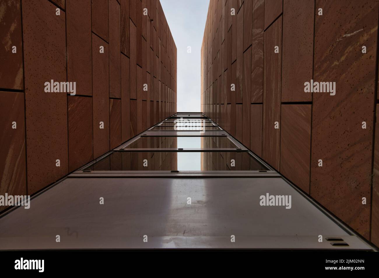 A low angle shot of a high rise glass building with reddish brick walls ...