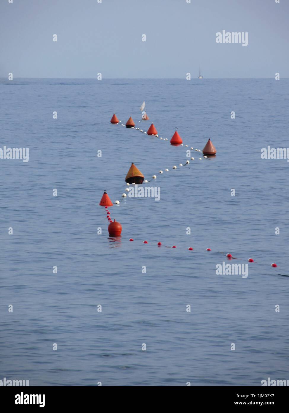 Lots of mooring buoys floating on water in marina. Small boat visible ...