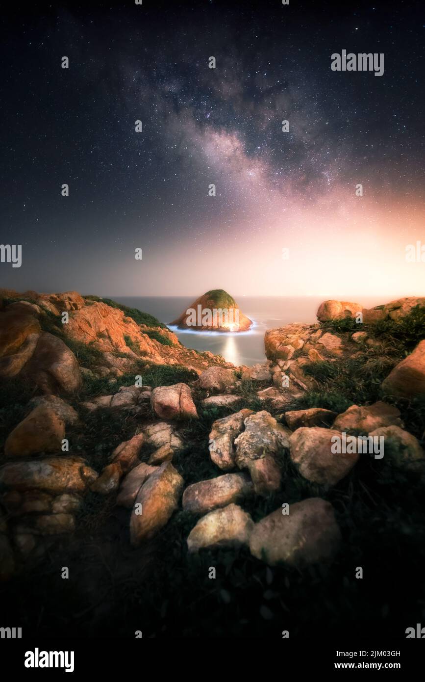 A gorgeous fantasy landscape with rocks in the calm sea under a bright ...