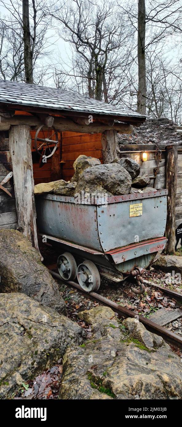 A trolley with big rocks on the railway tracks under a wooden roof ...