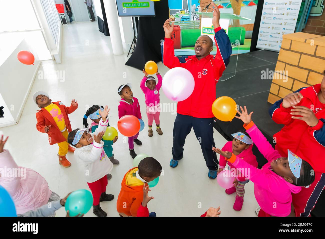 A group of young African children playing with balloons in the ...