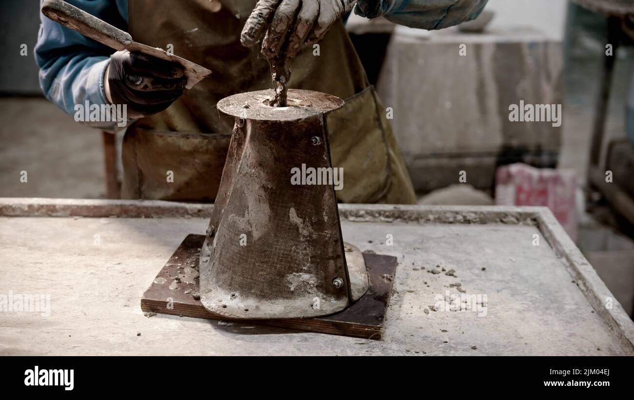 Concrete industry - worker putting concrete in the cone form and using ...