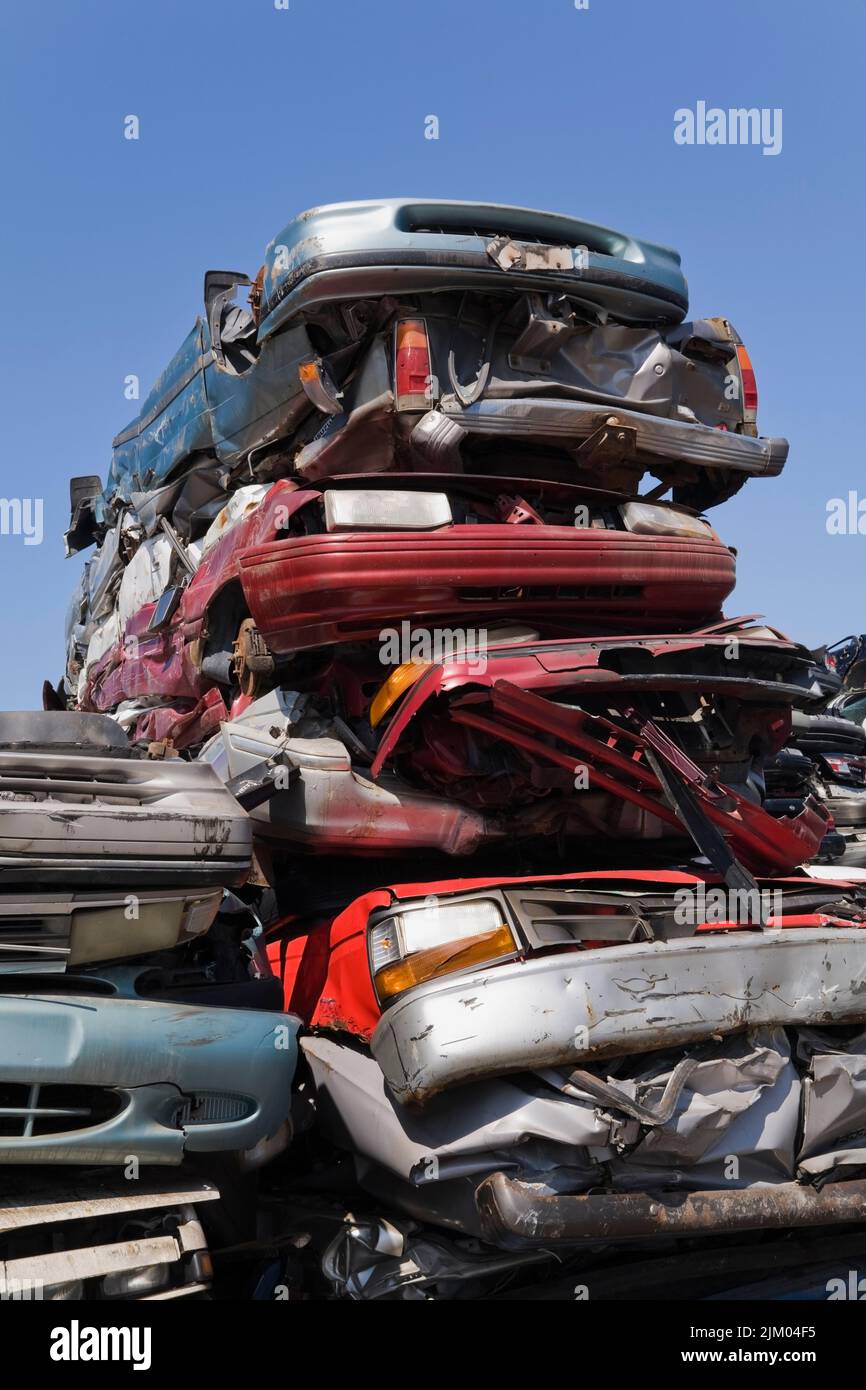 Stacked and crushed discarded automobiles at scrap metal recycling yard ...