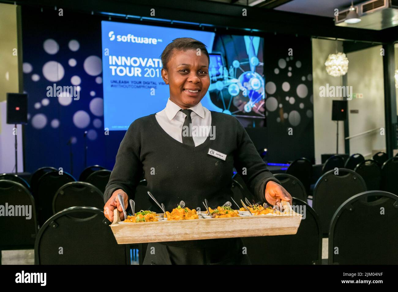 An African waitress holding a food tray and smiling at the camera Stock ...