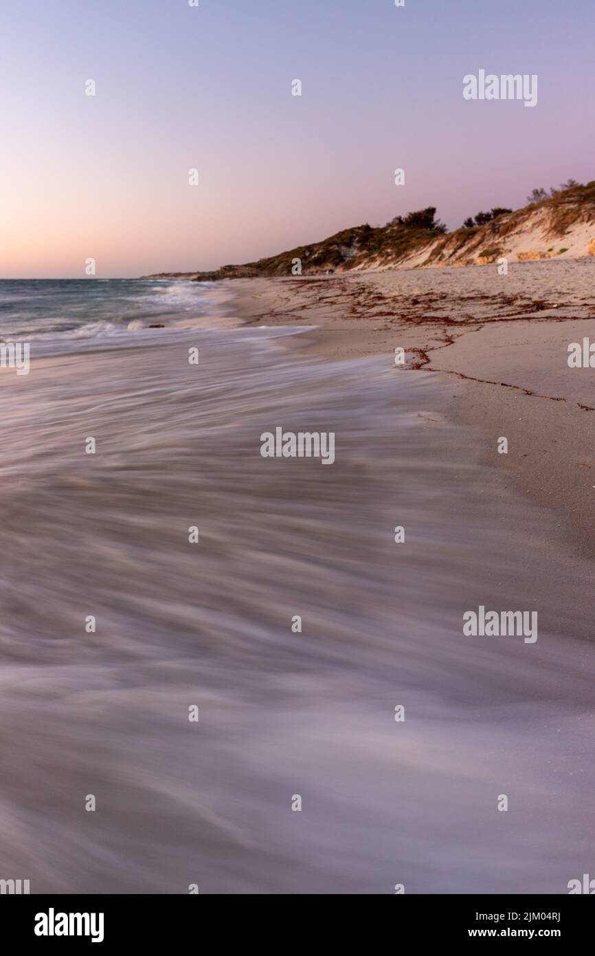 A vertical beautiful view of waves reaching the sandy beach under the ...