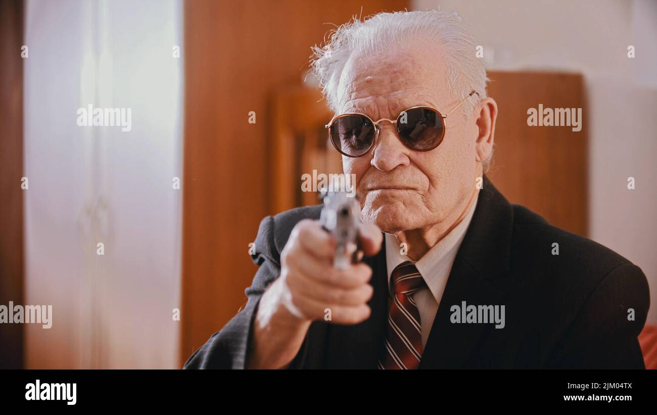 An old businessman aiming in the camera with a gun Stock Photo - Alamy