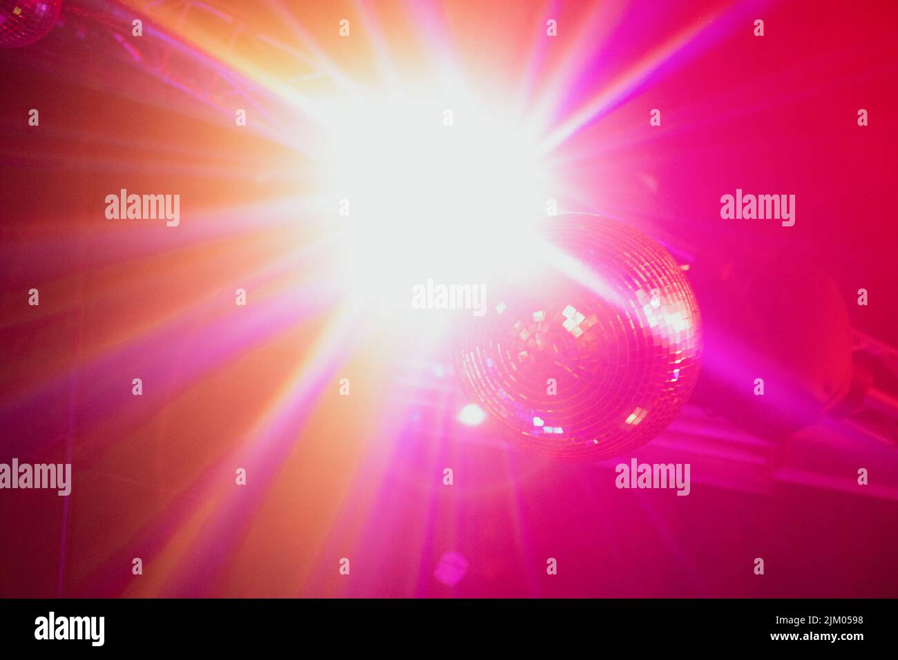 A closeup of the bright yellow and pink light in the club with a disco ...