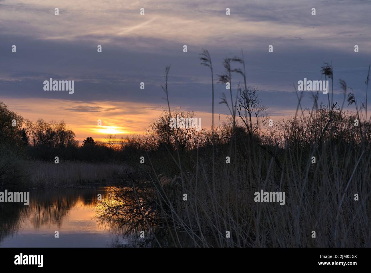 A warm summer sunset shining through the clouds with its reflecting in ...
