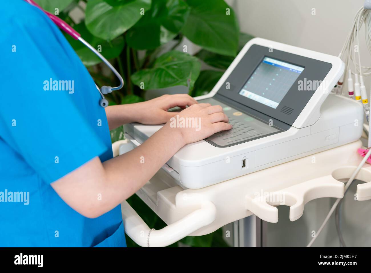 Doctor operating vital sign monitor in patient room of modern hospital ...