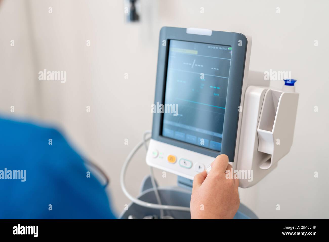 Doctor operating vital sign monitor in patient room of modern hospital ...