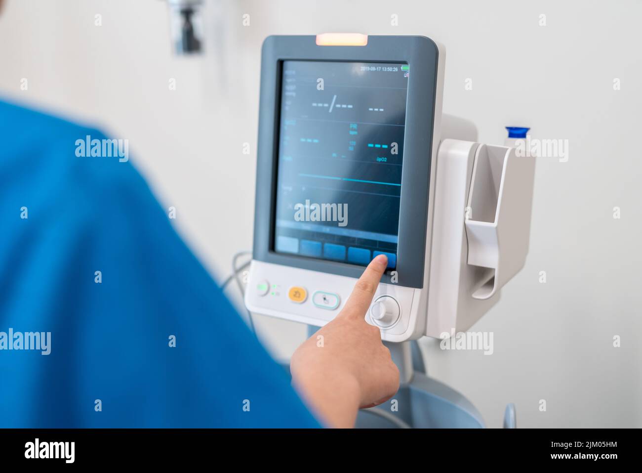 Doctor operating vital sign monitor in patient room of modern hospital ...