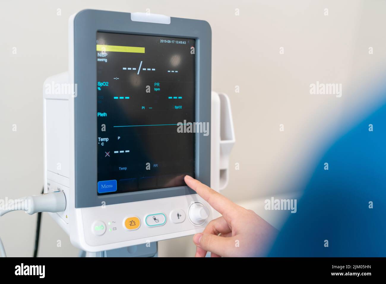 Doctor operating vital sign monitor in patient room of modern hospital ...